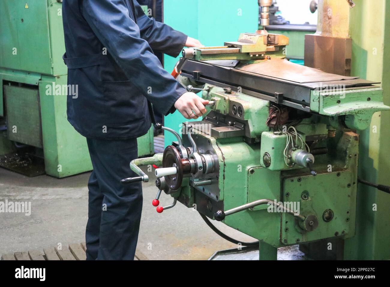 A male worker works on a larger metal iron locksmith lathe, equipment ...