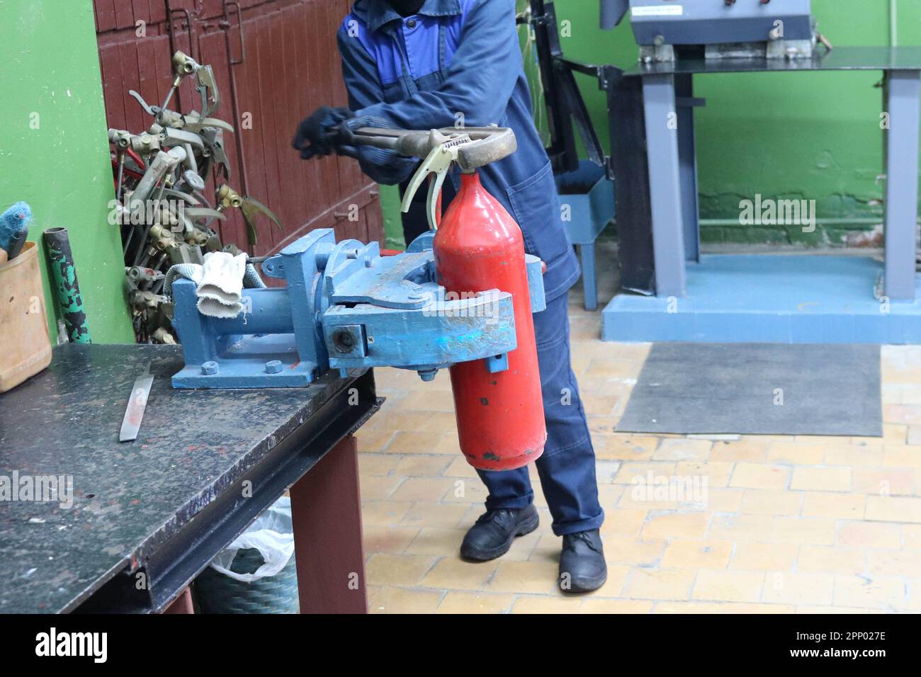 A man working on a large metal industrial vice with a huge gas wrench ...