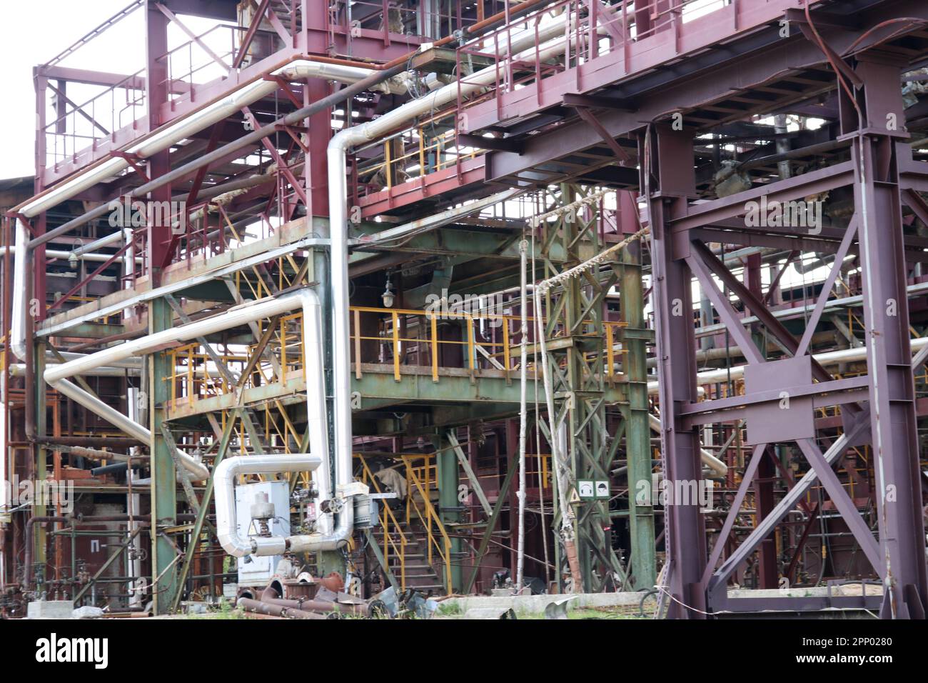 A large iron metal piping trestle with pipes and electric wires and ...