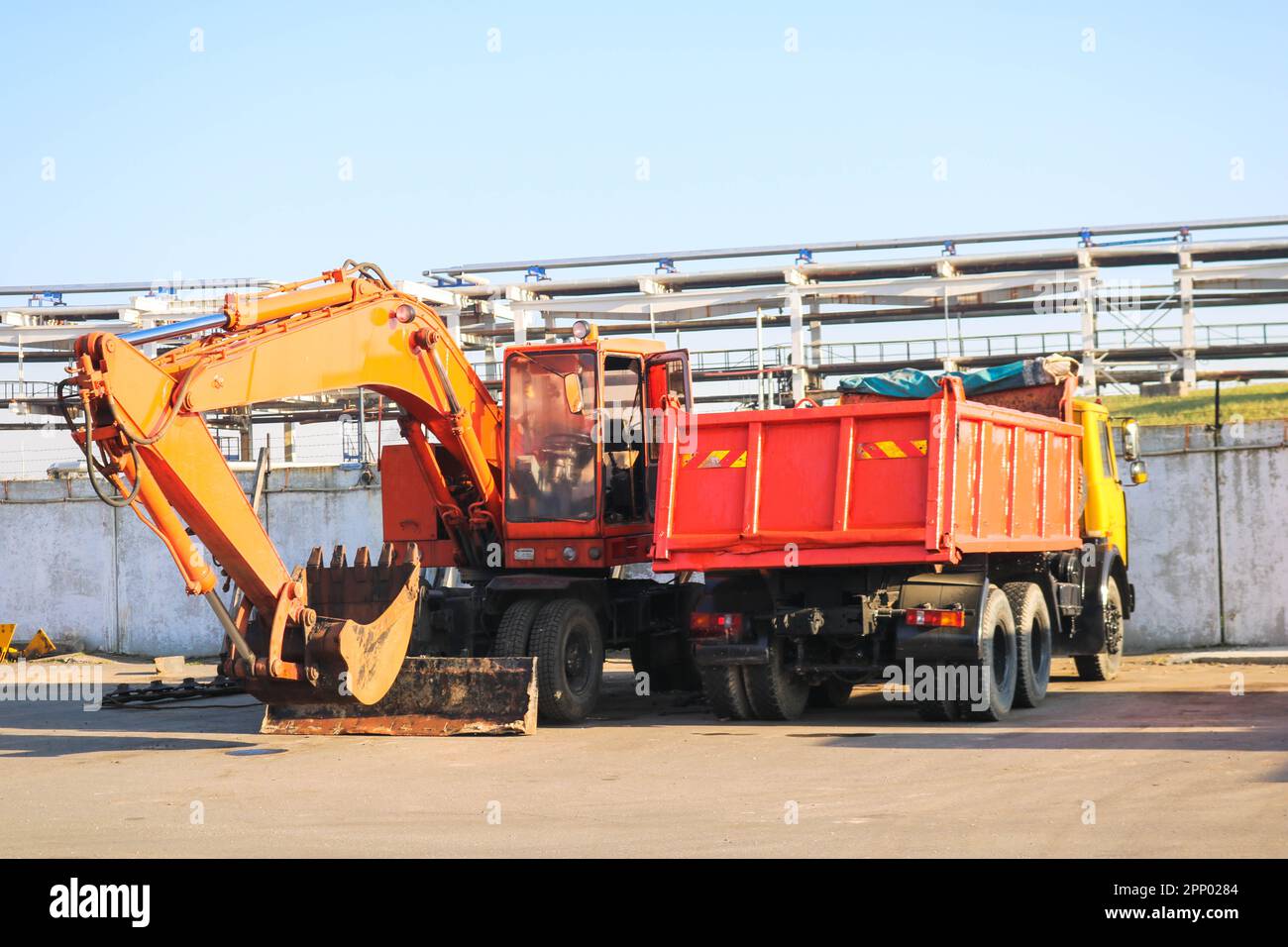 A large heavy yellow orange truck with a trailer, a dump truck and an ...