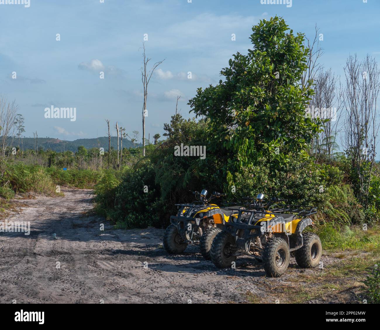 A line of four-wheel drive all-terrain vehicles parked on a dusty road ...