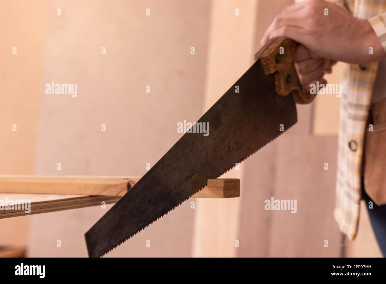 Crop anonymous craftsman using sharp saw while cutting timber plank in ...