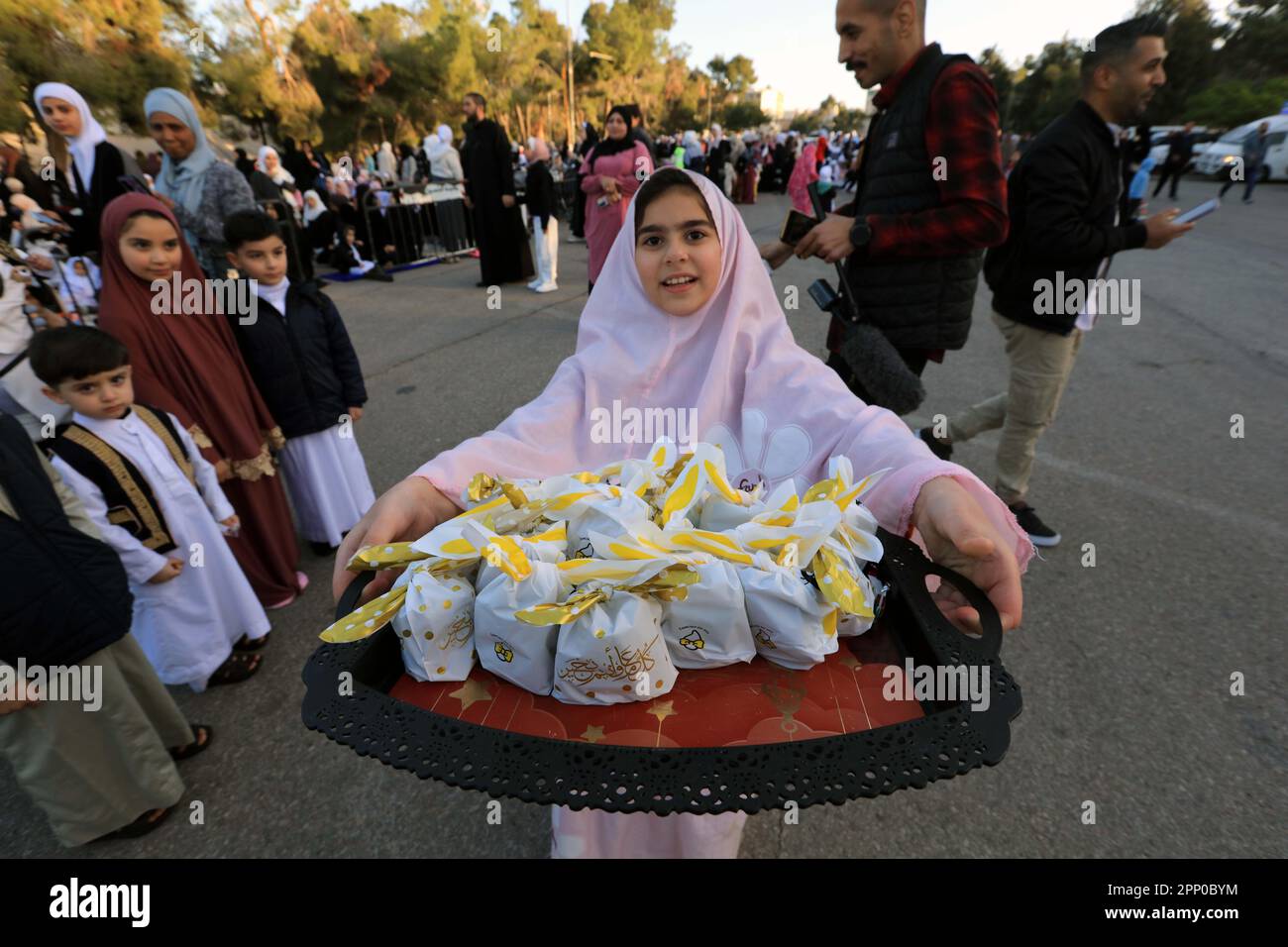 Amman, Jordan. 21st Apr, 2023. A girl distributes sweets after offering ...