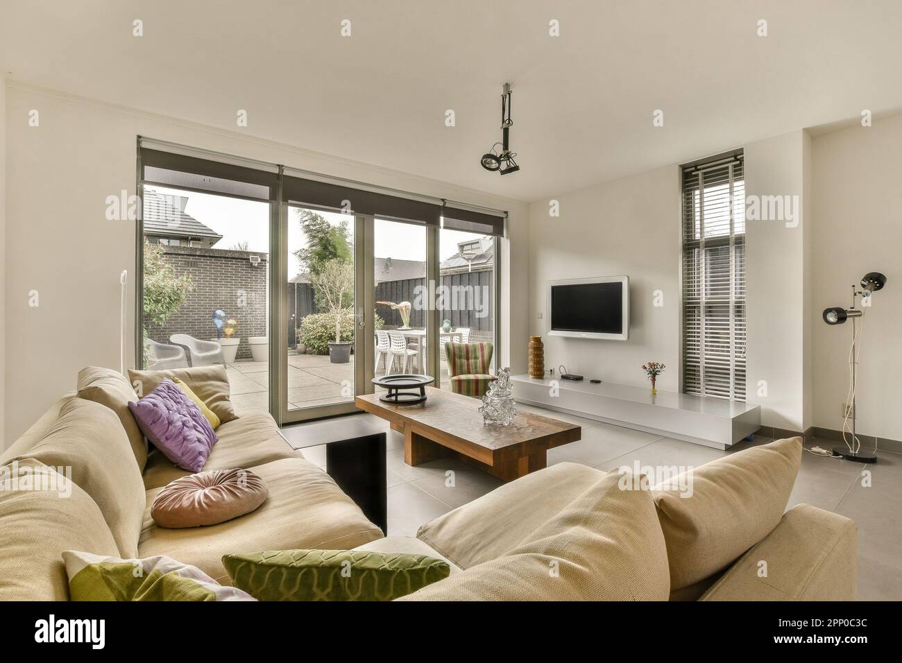 a living room with couches, tv and sliding glass doors that open out ...