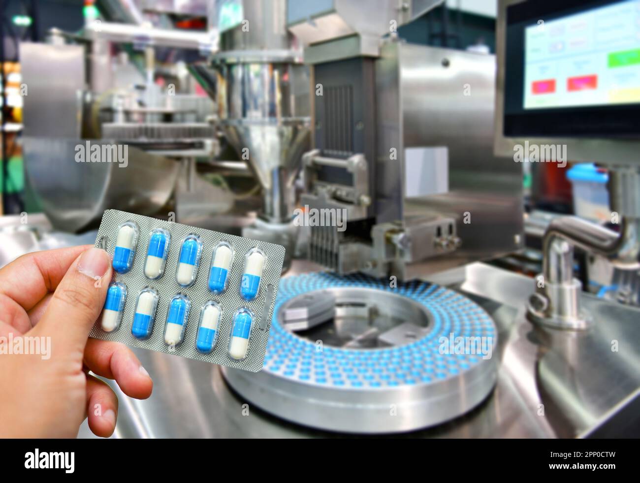 Hand holding blue capsule pack at medicine pill production line ...