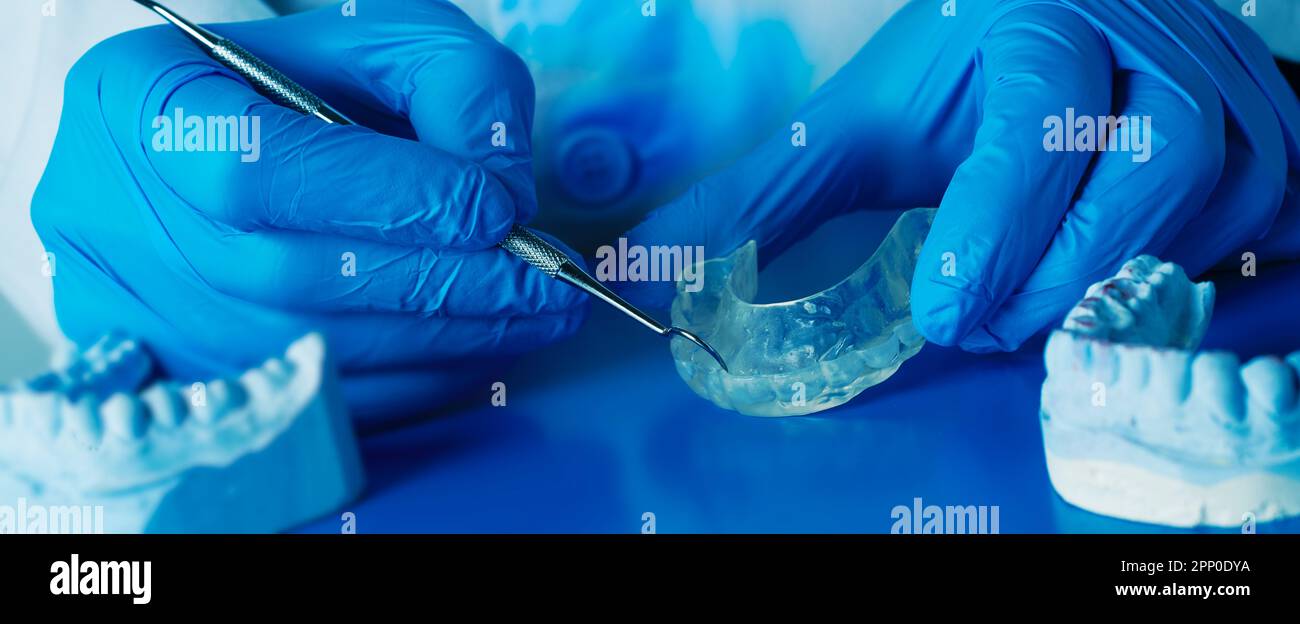 a dentist is adjusting an occlusal splint, using a metal tool, in a ...