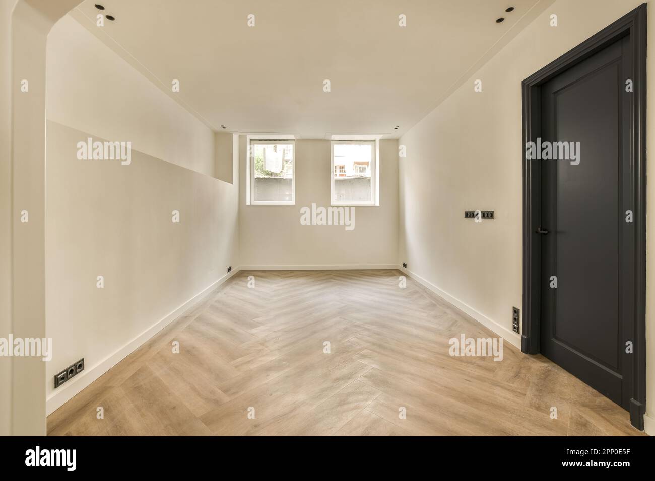 an empty room with wood flooring and white walls, there is a black door ...