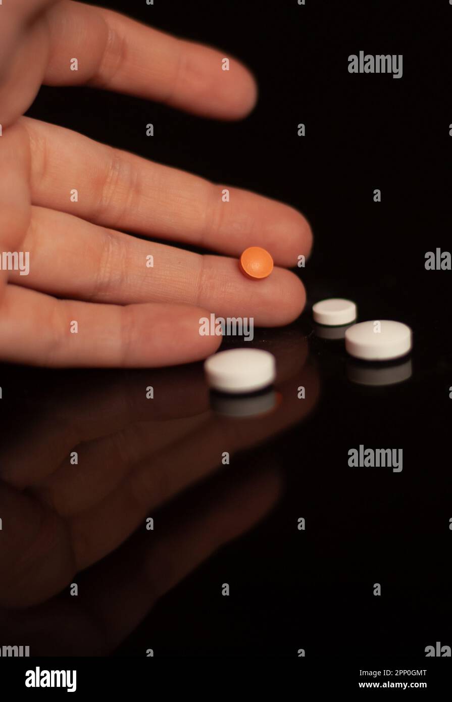 View of red pill on a hand on the black background Stock Photo - Alamy