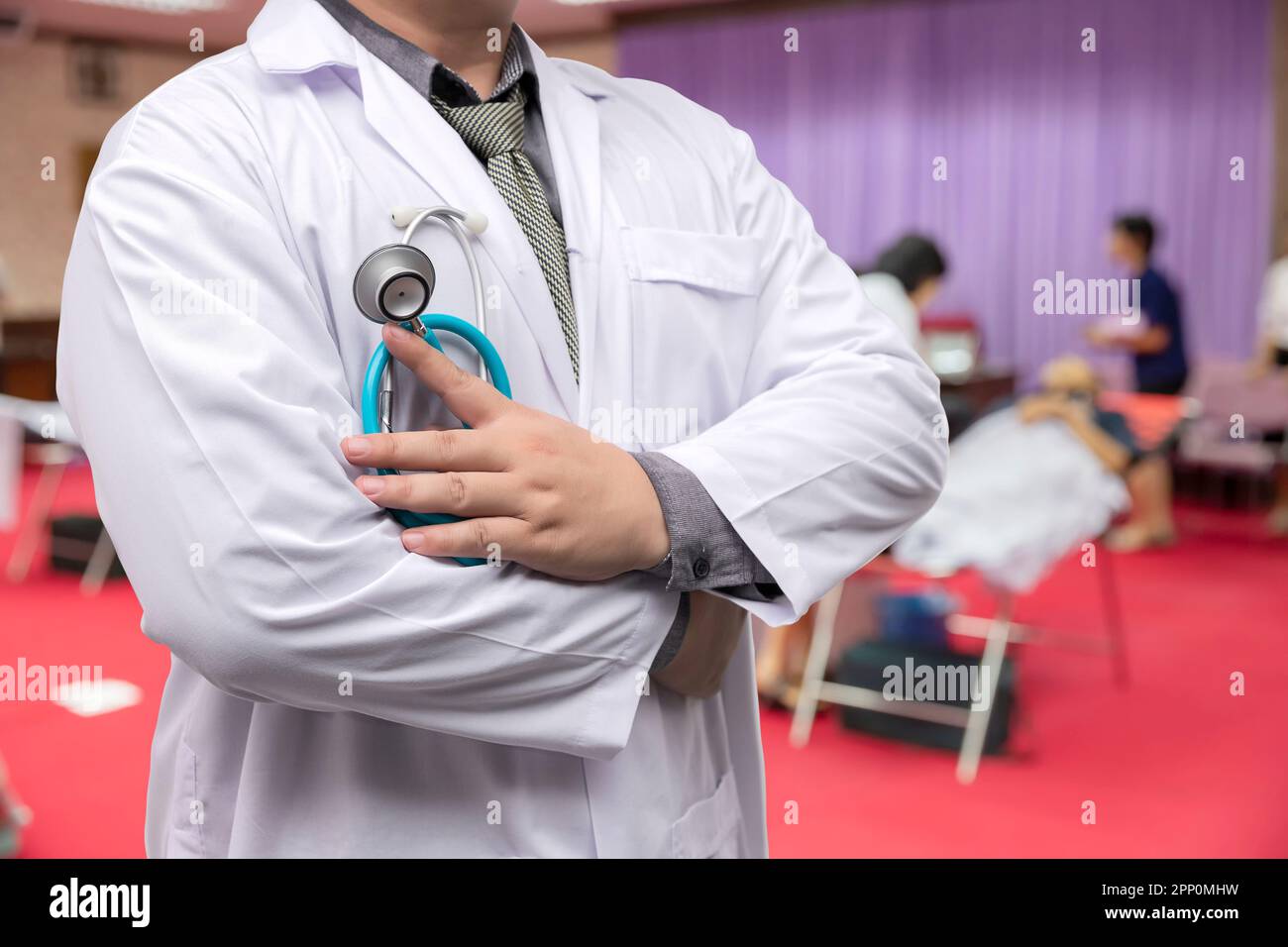 Doctor in gown uniform with stethoscope standing and fold his arms over the chest in blood donor ...