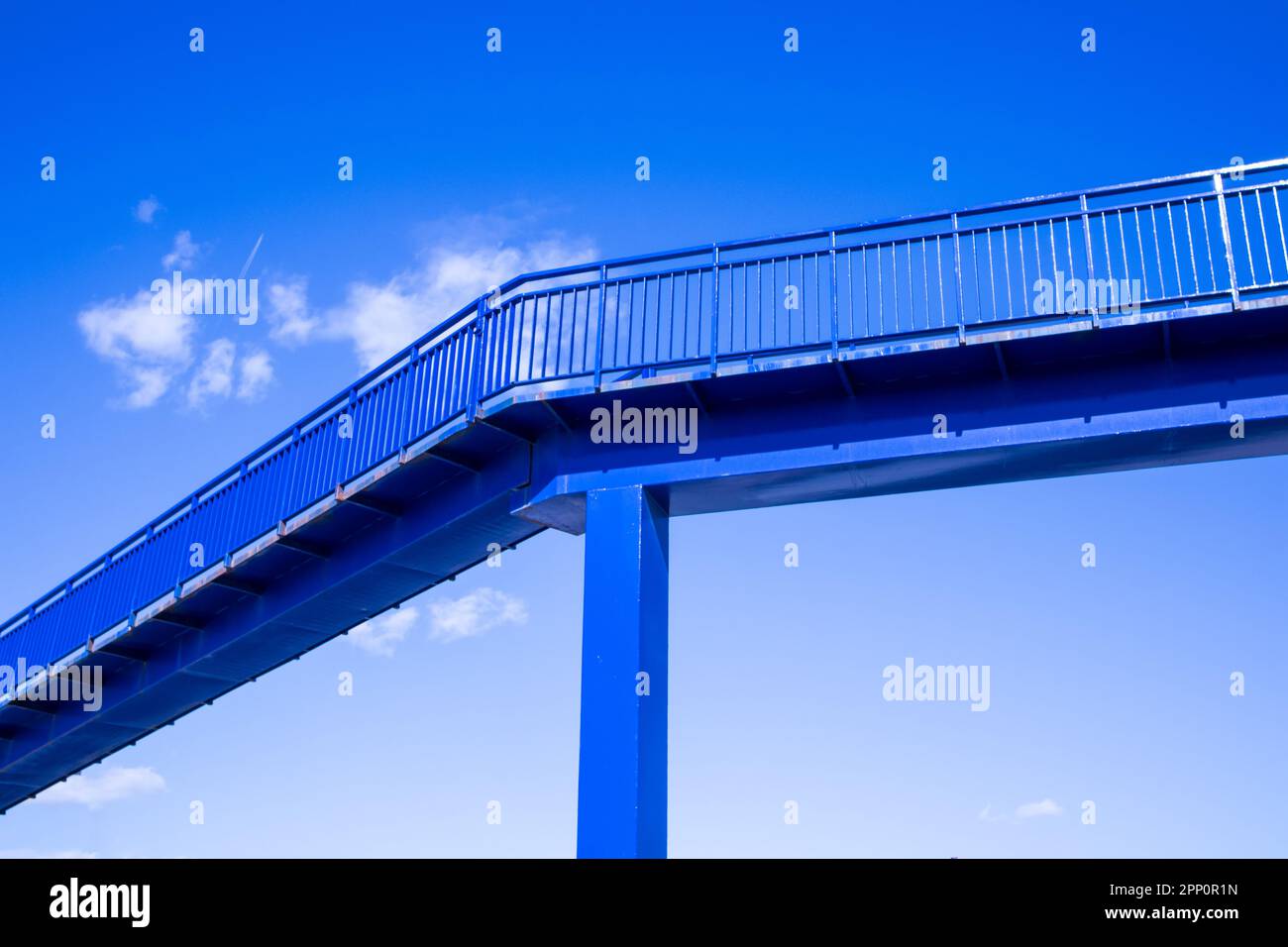 A modern pedestrian overpass across a highway. Blue bridge without ...