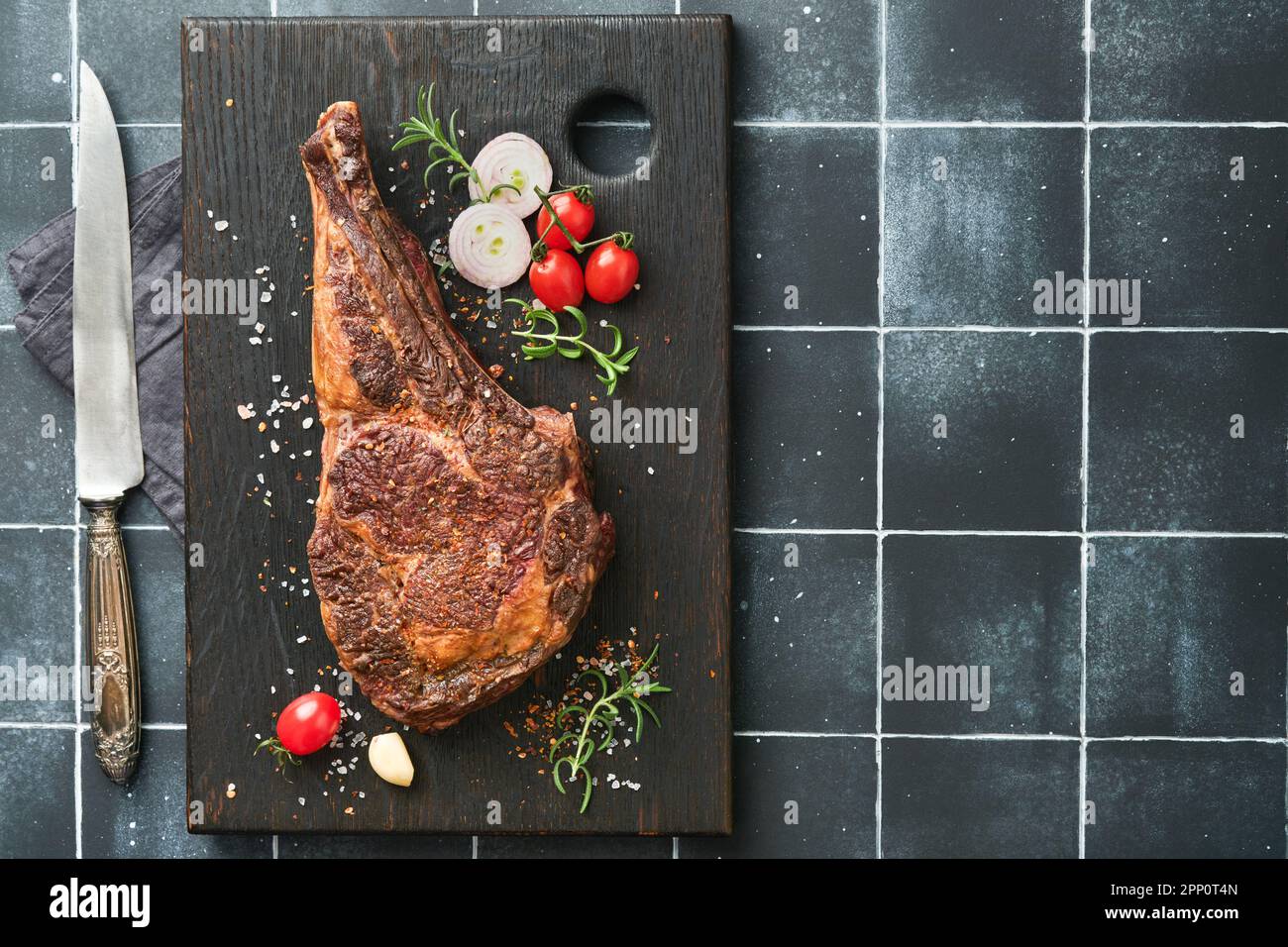 Tomahawk steak. Sliced grilled tomahawk beef steak with baked cherry ...