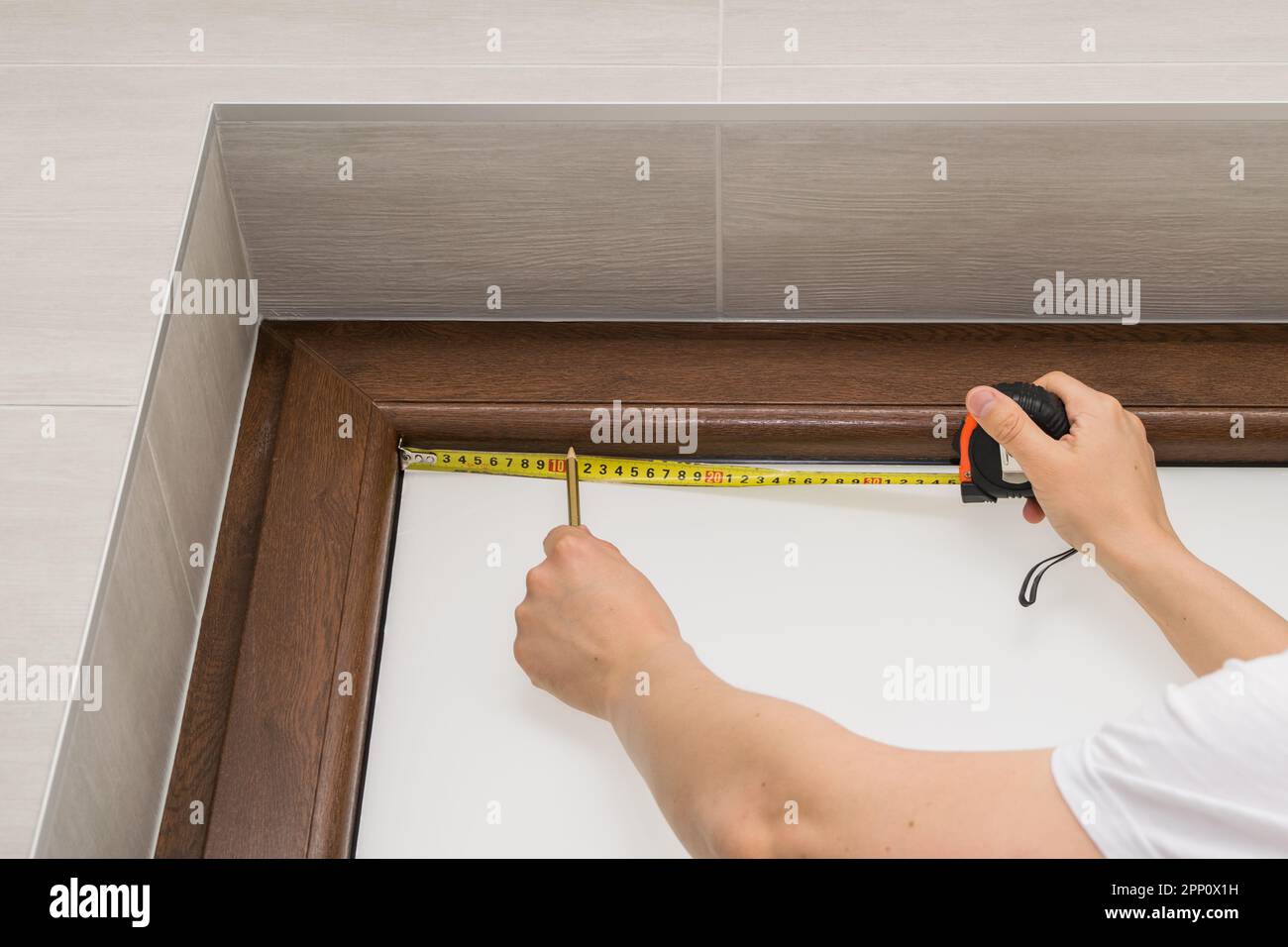 View of a man measuring a brown plastic window with a tape measure ...