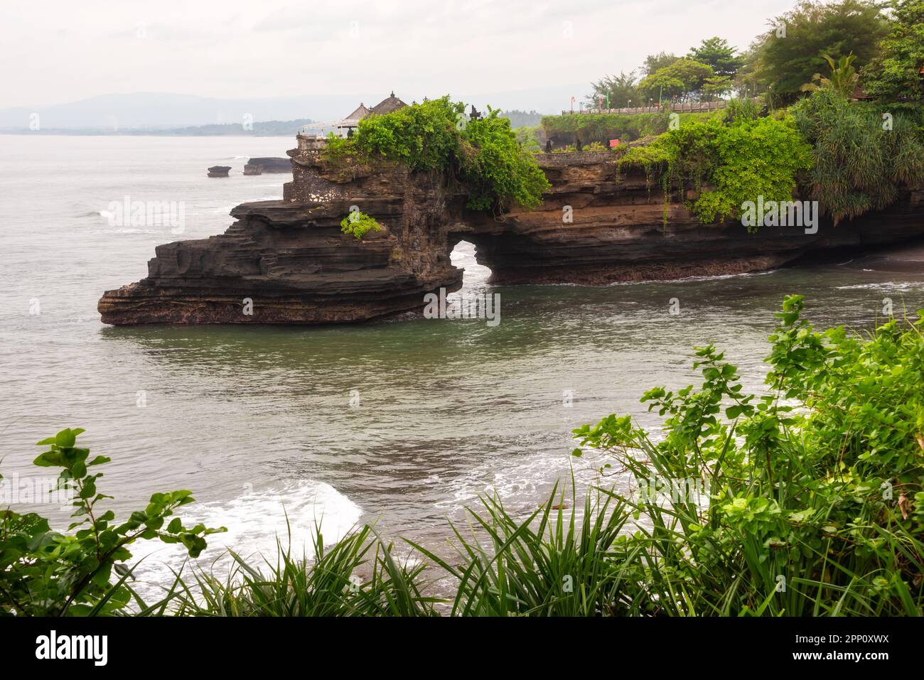 Arch rock with a temple and green plants on Bali island, Indonesia ...