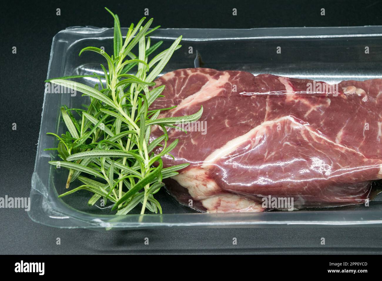 Beef steak, view of fresh beef in foil wrapper on a dark background with rosemary Stock Photo ...