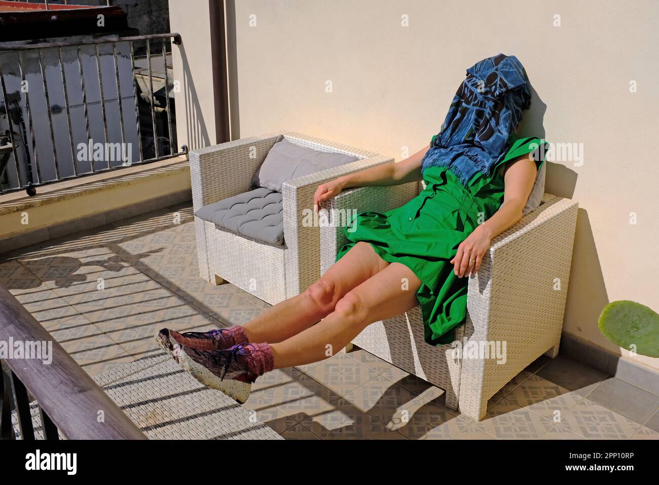 A woman sunbathing with a cloth on her head, face, to offer protection ...