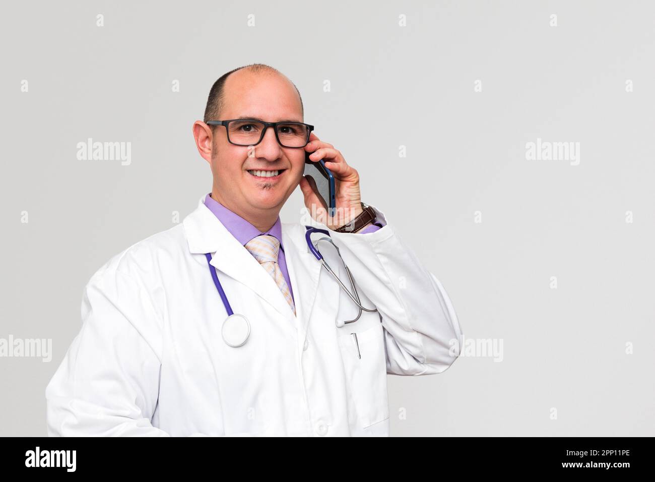 A bald male smiling caucasian doctor with eyeglasses wearing a white ...