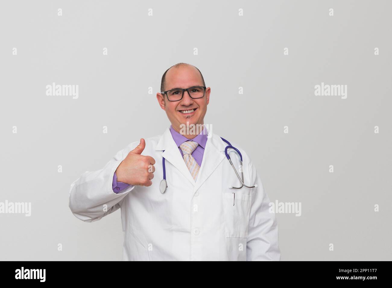 A bald male smiling caucasian doctor with eyeglasses wearing a white ...
