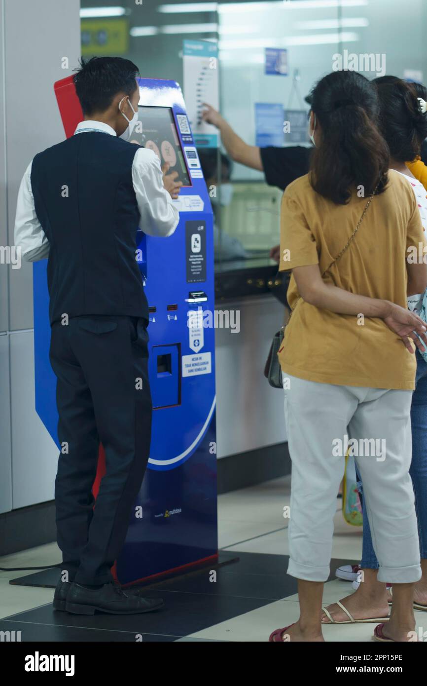 An officer is helping people at the ticket machine at the MRT Station ...