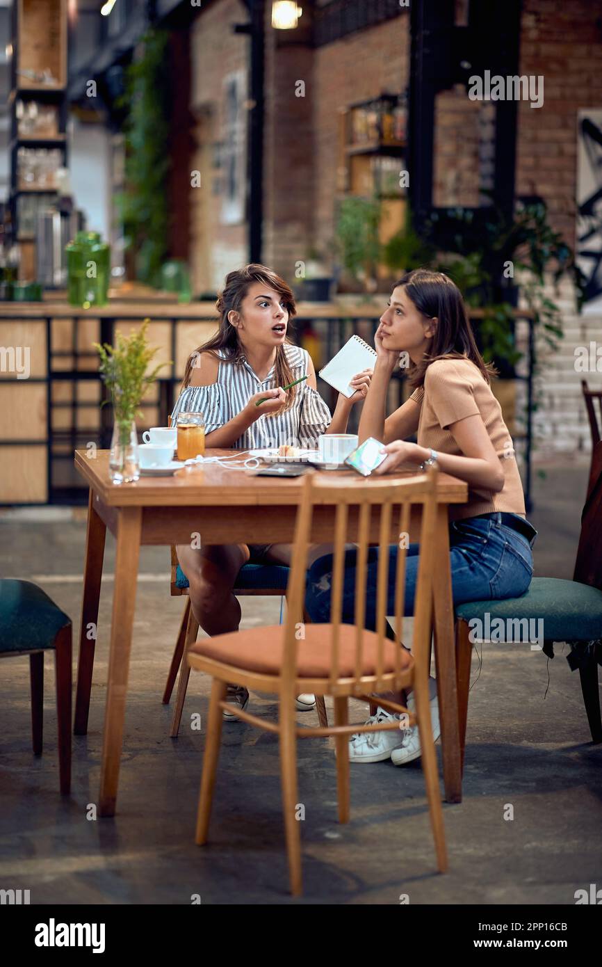 Two young woman in cafe talking or discussing something serious. Woman ...
