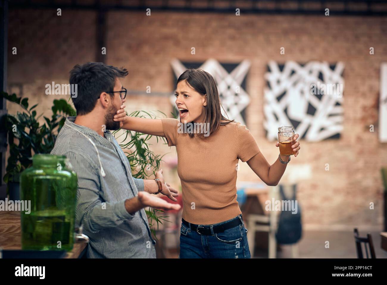 Young couple in a bar having an argument. Woman mad at man and holding ...