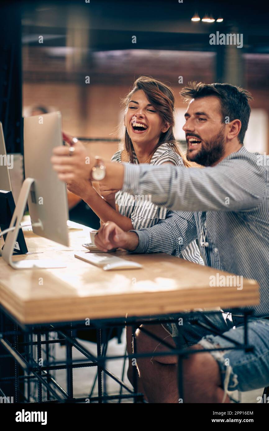 Young beautiful man and woman colleagues at work looking at screen of ...