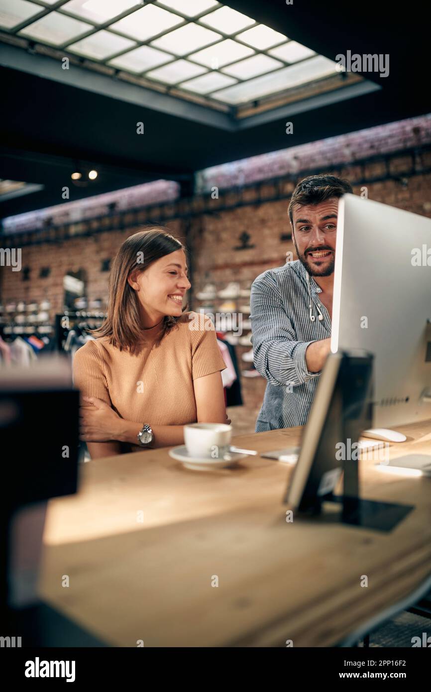 Excited young teammates working together on desktop computer. Young man ...