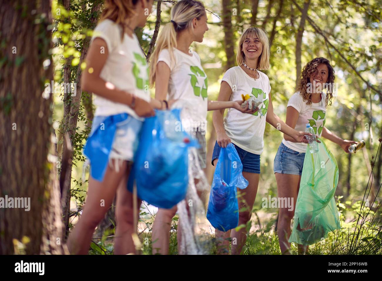 Young volunteers collecting garbage in park.Group of smiling woman ...