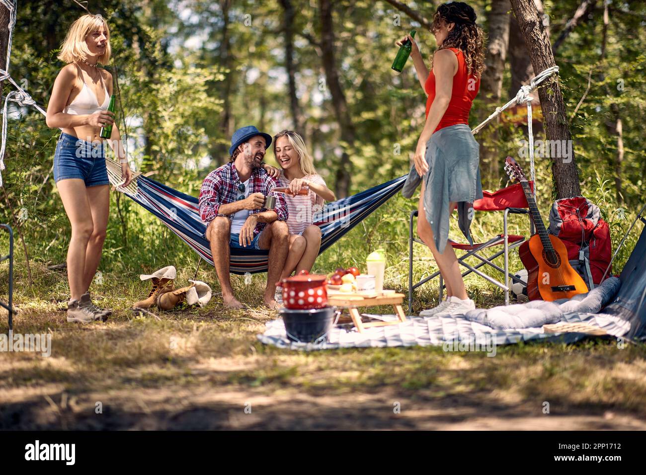 camping, tourism and travel concept - young friends have good time on ...