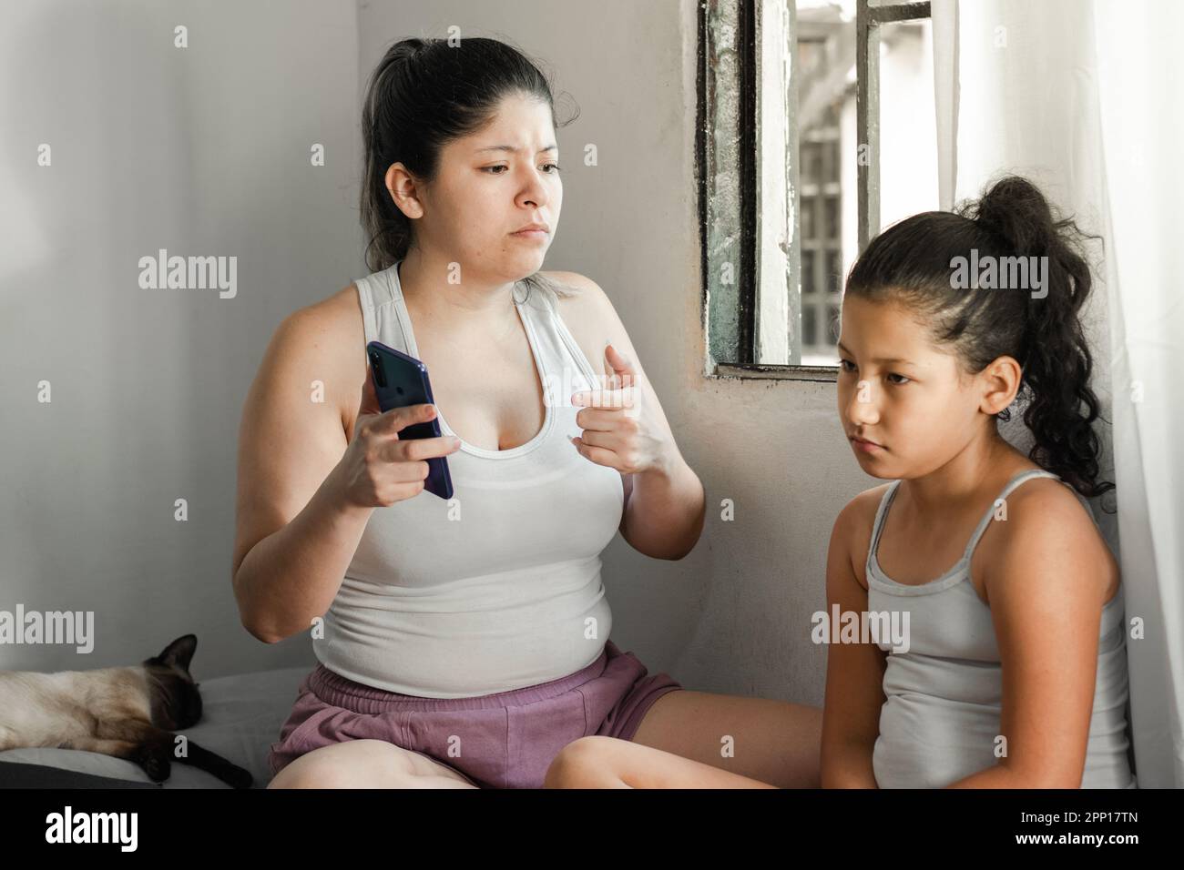 mother scolding daughter while pointing at cell phone and child gets very angry Stock Photo - Alamy