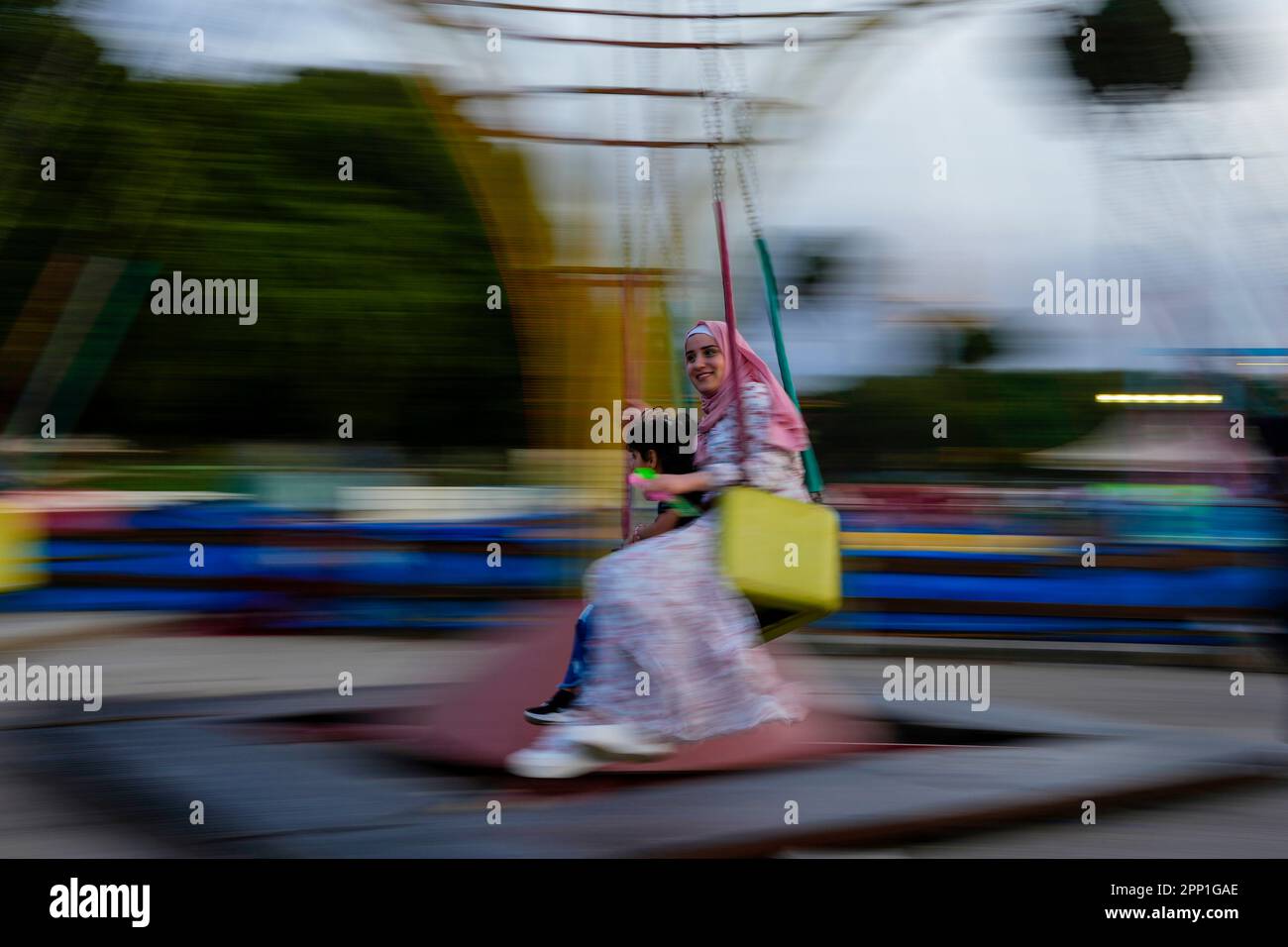 A Muslim woman enjoys the swing ride at an amusement park as she ...