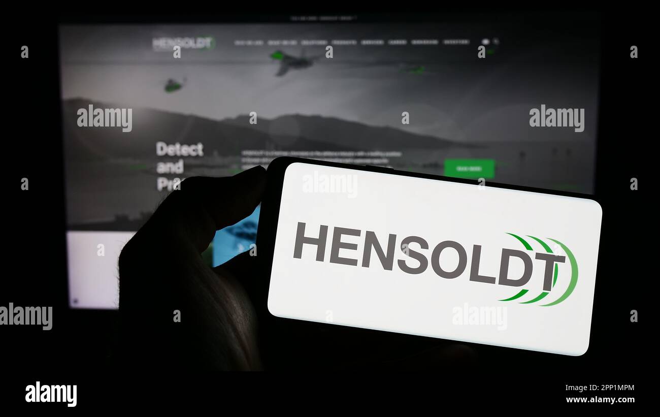 Person holding smartphone with logo of German defense company Hensoldt ...