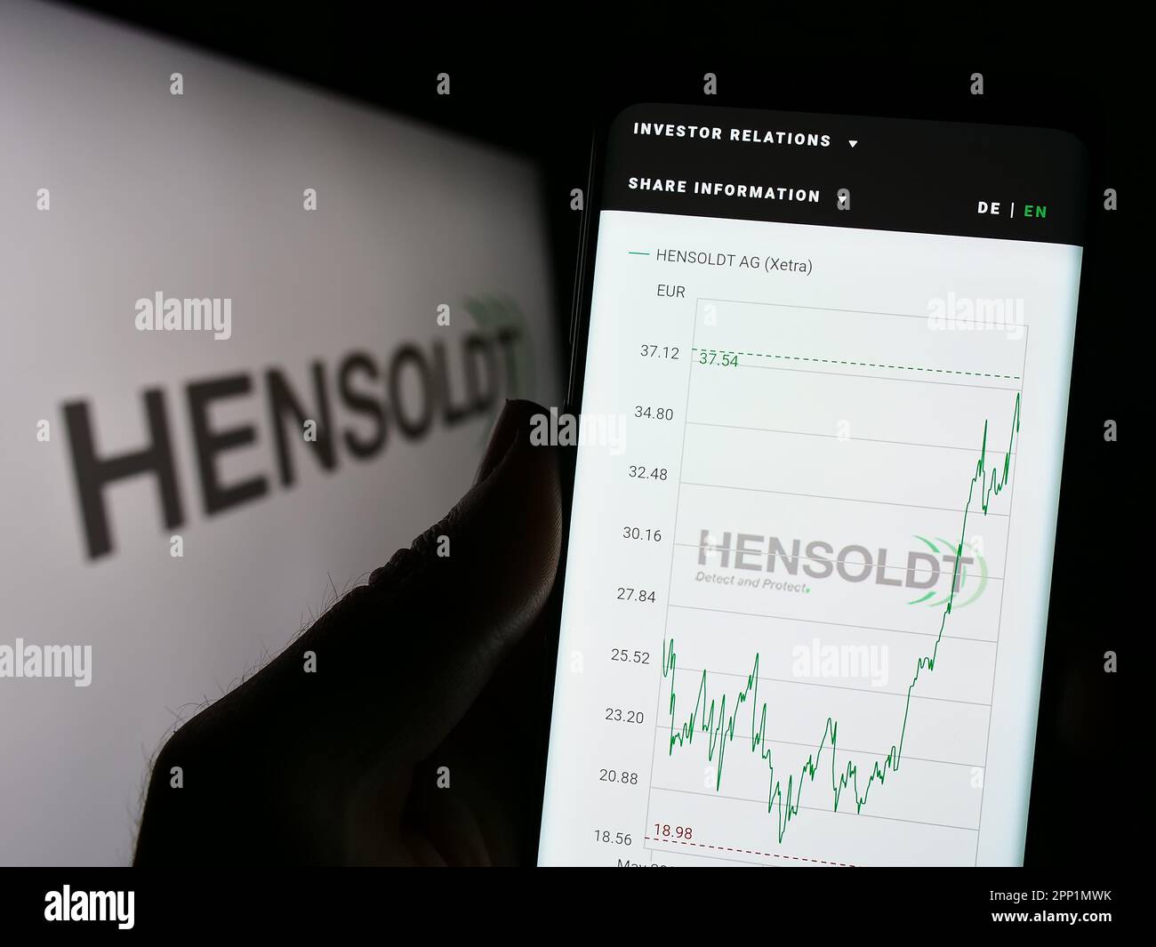 Person holding cellphone with webpage of German defense company ...