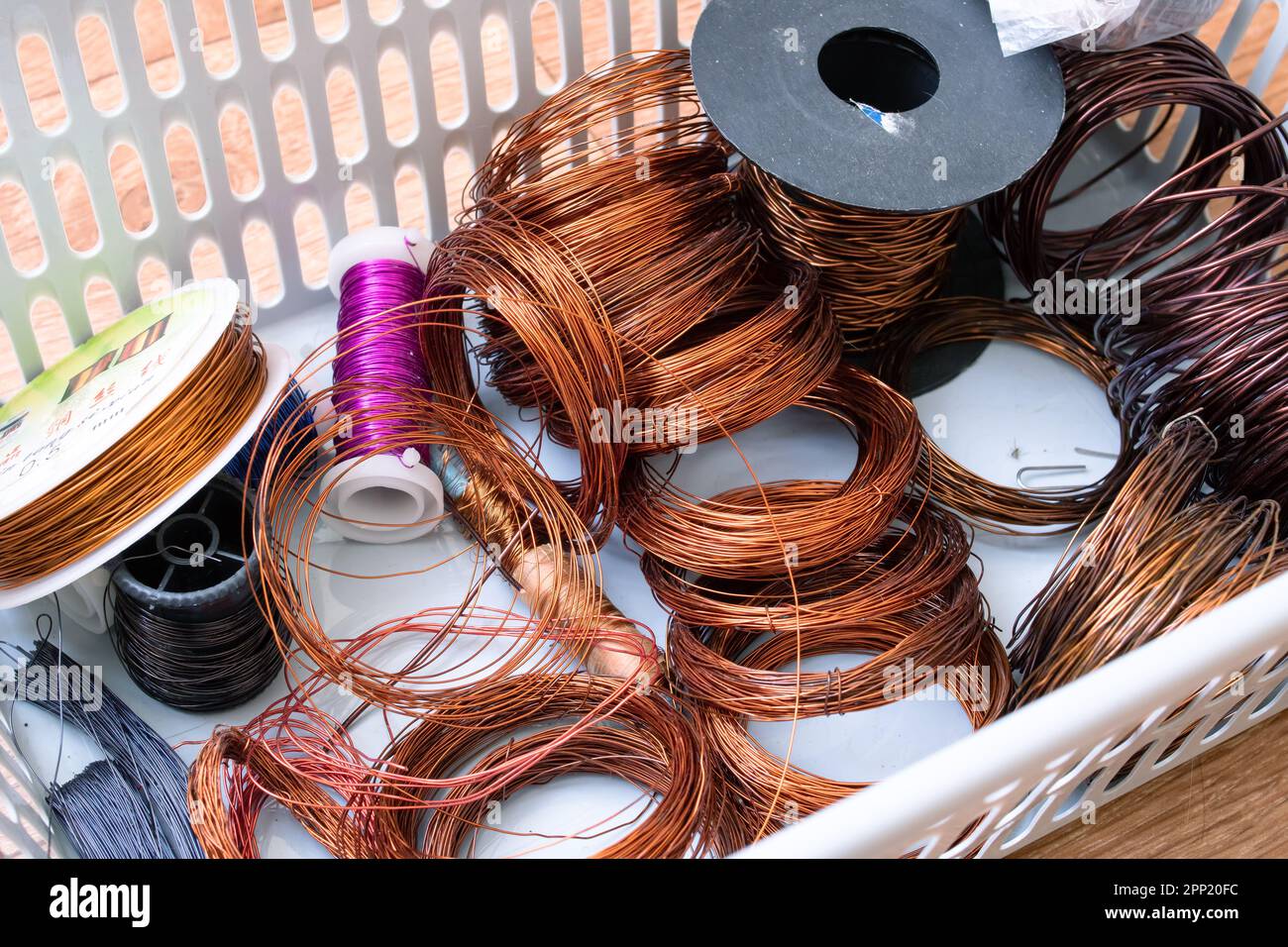 Copper wire coils in a plastic basket close up Stock Photo - Alamy