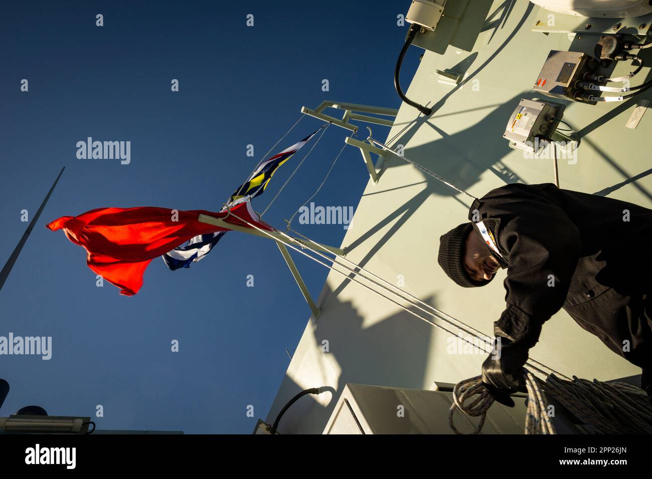 Sailor raising a hoist of signal flags onboard HMCS Margaret Brooke ...