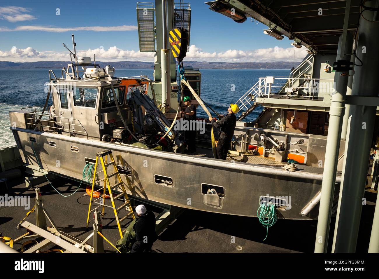 Sailors use the hydraulic crane at the stern of HMCS Margaret Brooke to ...