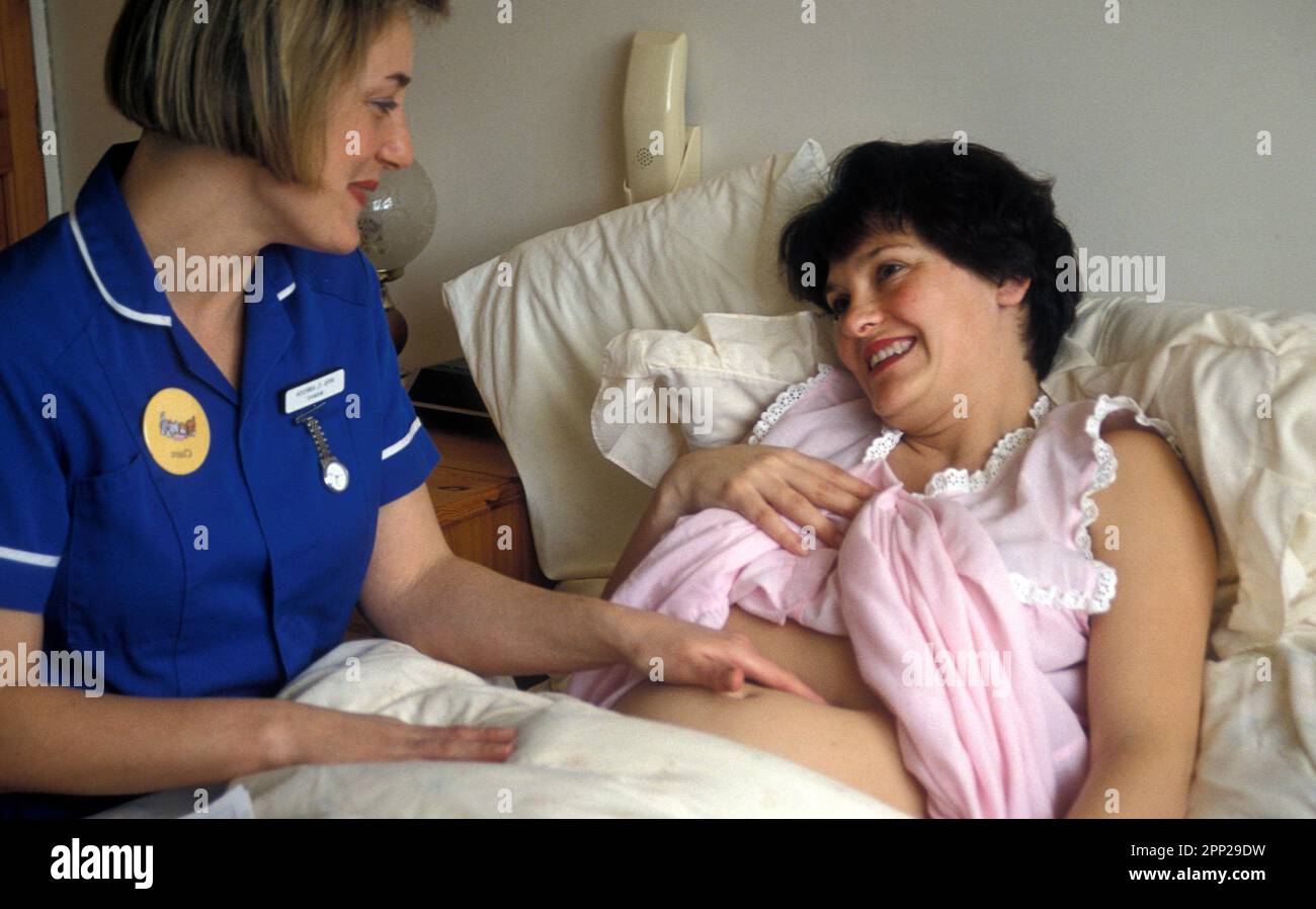 community midwife on home visit checking fundal height of woman's ...