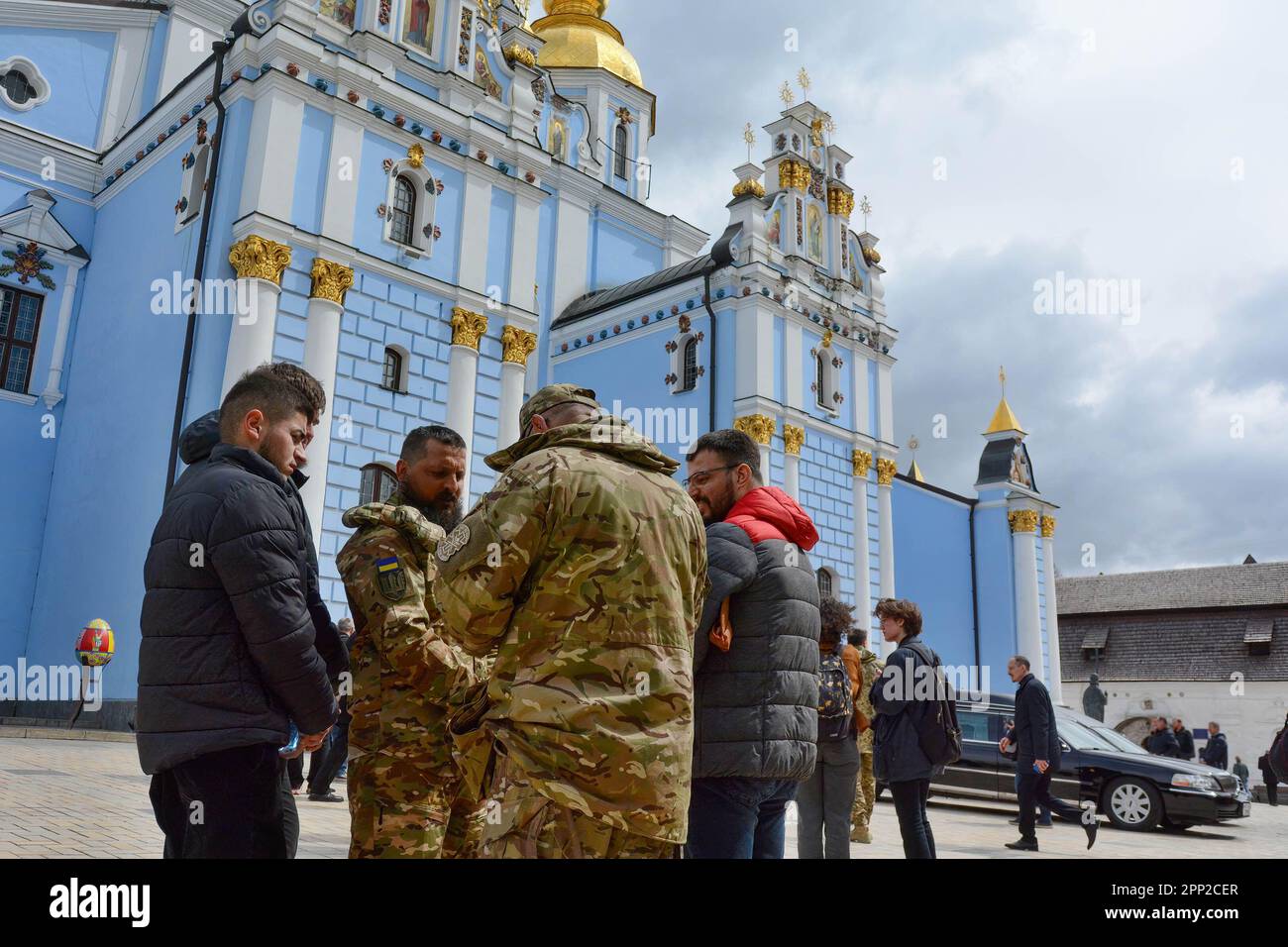 Military and civilians stand against the backdrop of the Mykhailivskyi ...