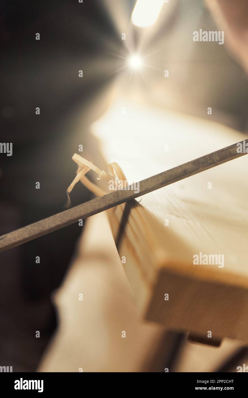 The carpenter uses a manual cutting tool to chamfer and carve the edges ...