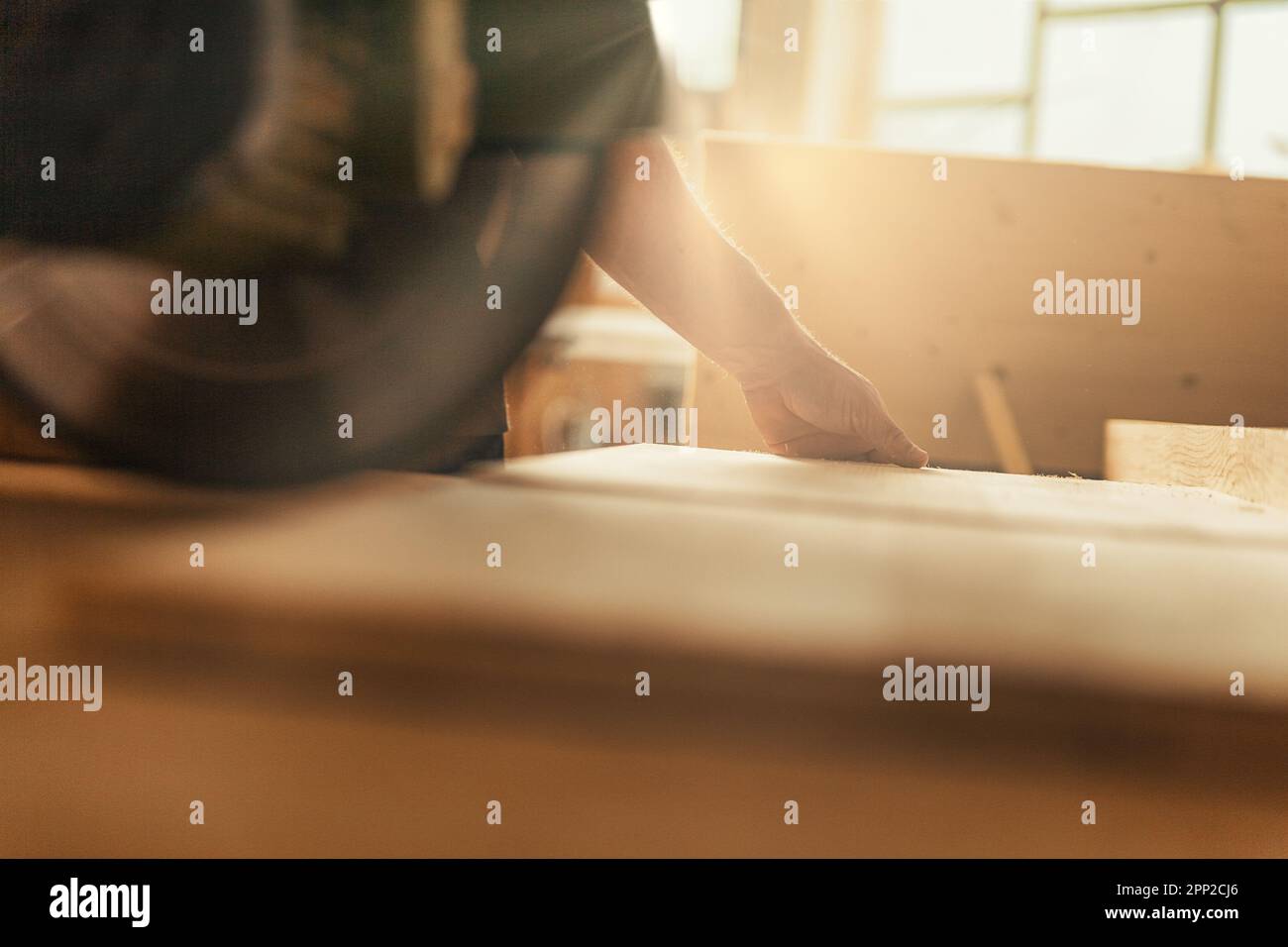 The carpenter guides a wooden board with a strong and confident hand as ...