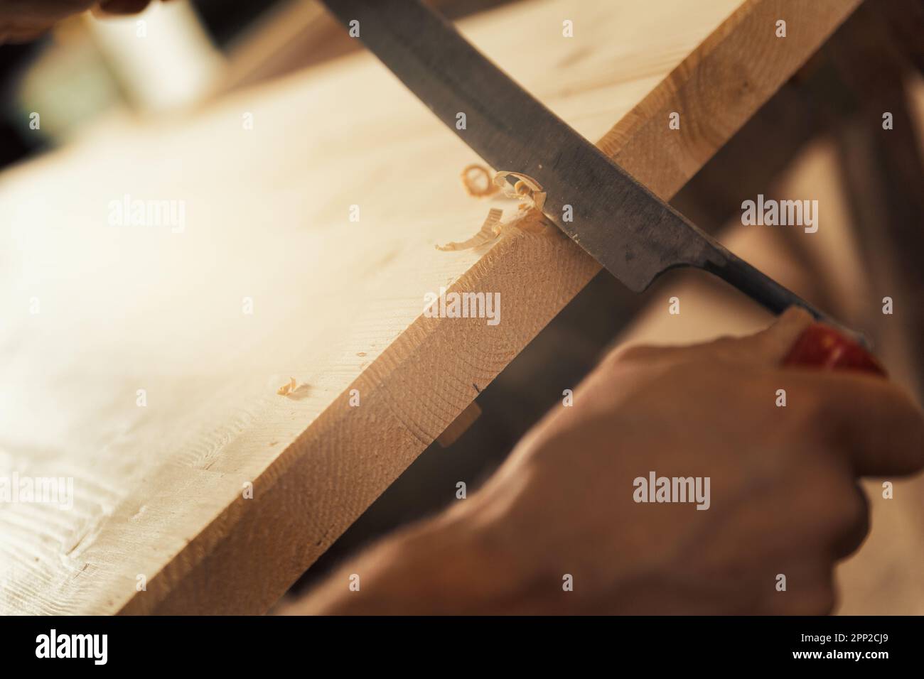 The carpenter uses a manual cutting tool to chamfer and carve the edges ...