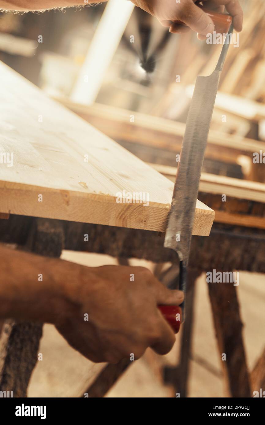 The carpenter uses a manual cutting tool to chamfer and carve the edges ...