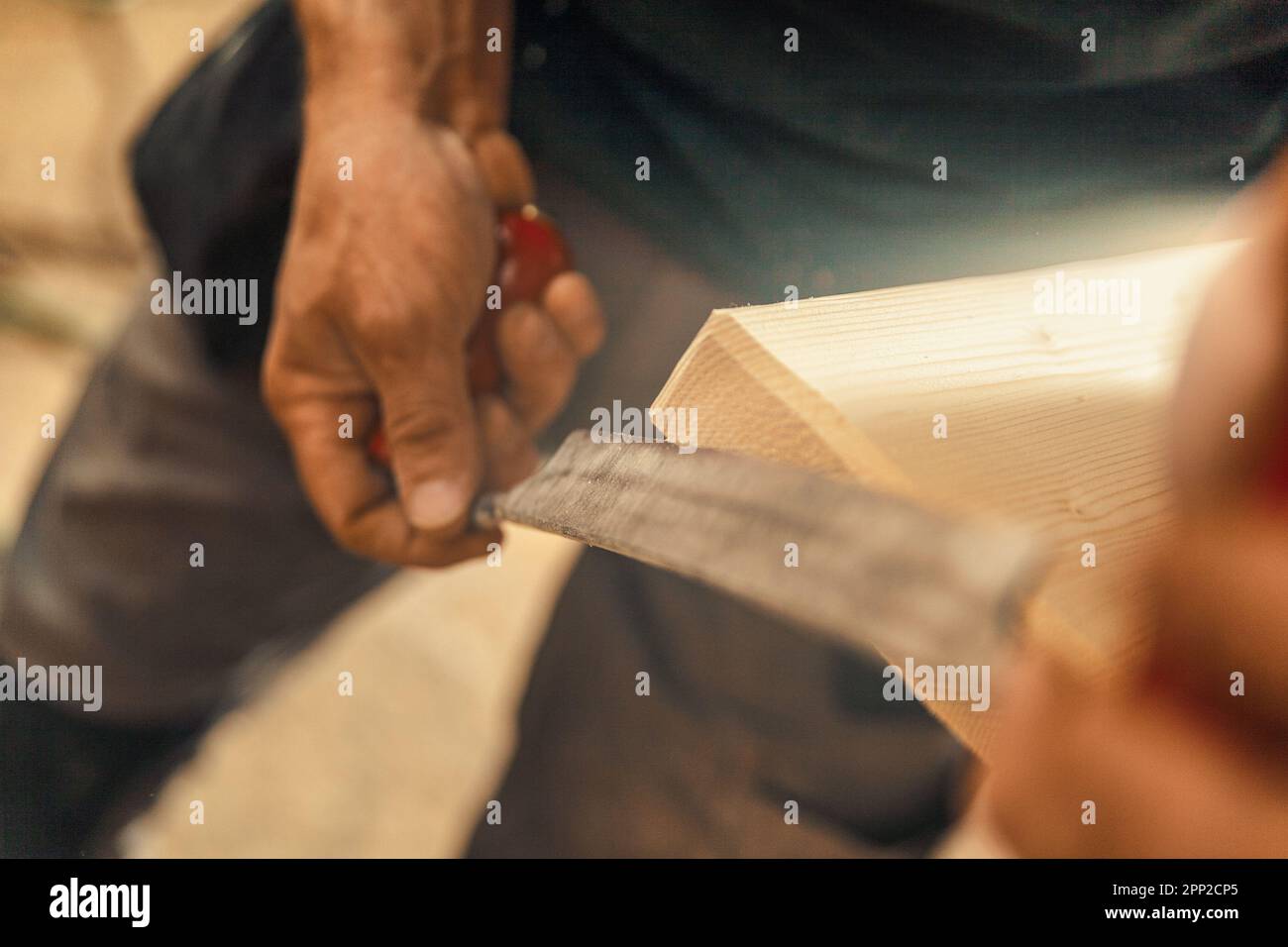 The carpenter uses a manual cutting tool to chamfer and carve the edges ...