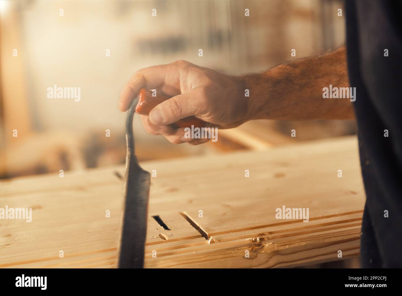 The carpenter uses a manual cutting tool to chamfer and carve the edges ...