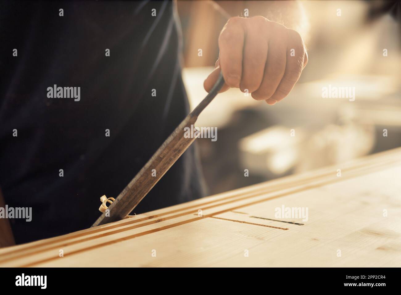 The carpenter uses a manual cutting tool to chamfer and carve the edges ...