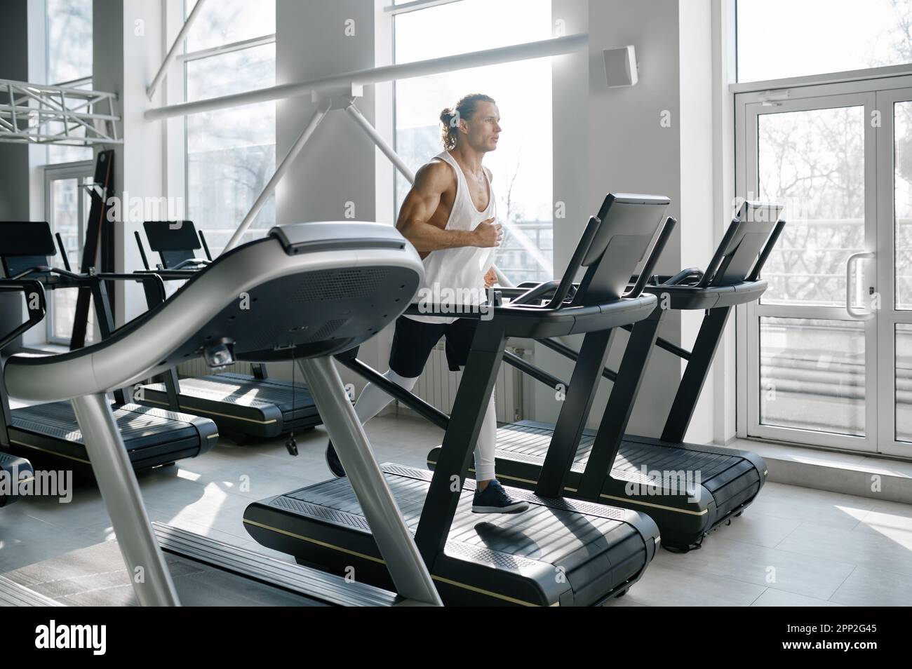 Strong muscular man running on treadmill at modern sport gym Stock ...