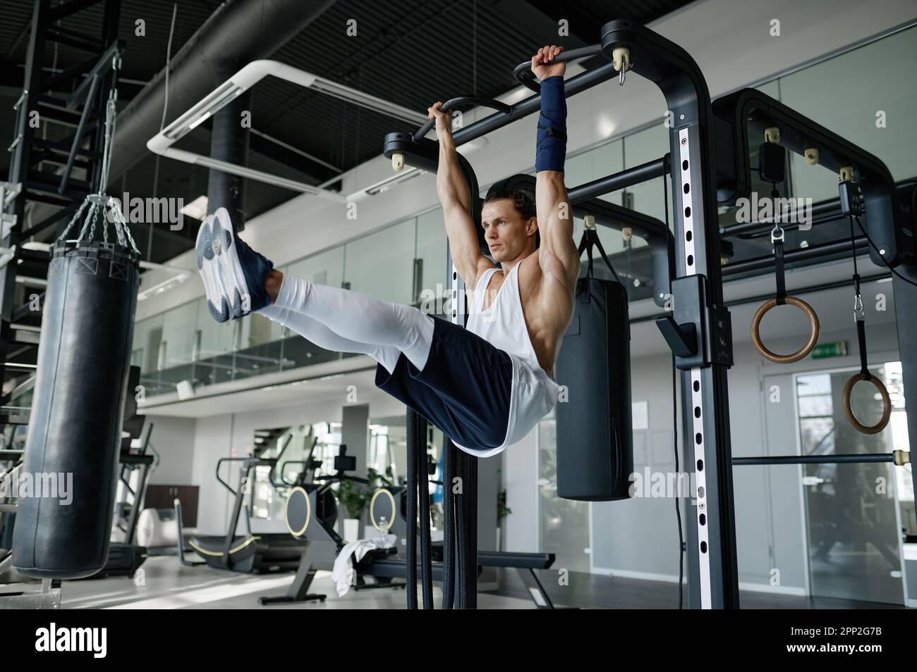 Strong energetic sportsman with perfect body pulling up on bar at sport ...