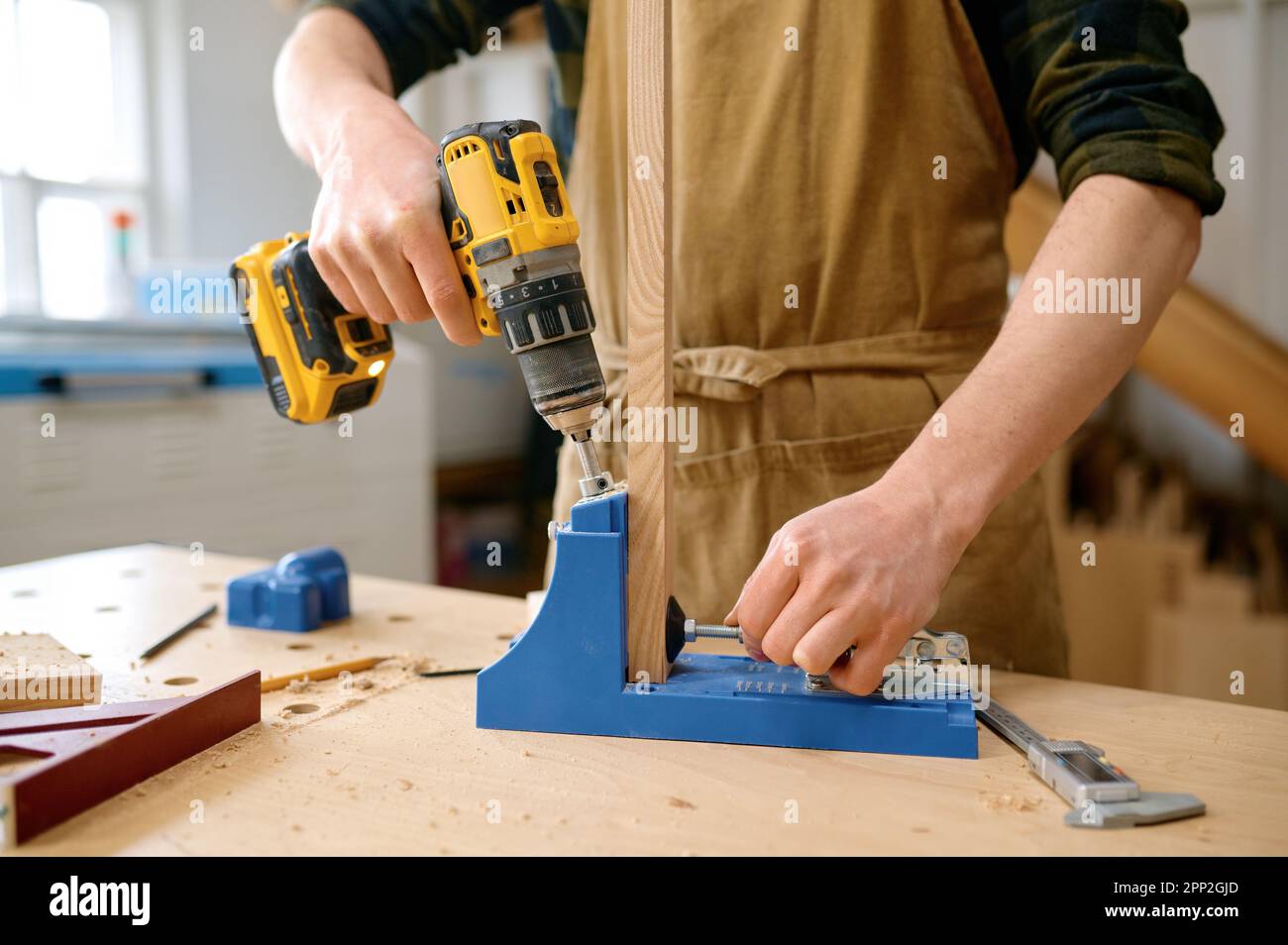 Man carpenter making holes in wooden plank using electric instrument ...