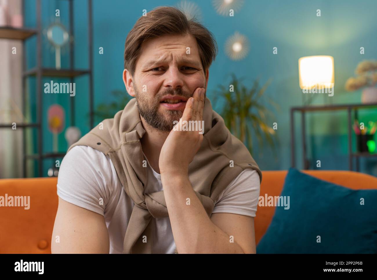 Dental problems. Young man touching cheek, closing eyes with expression ...