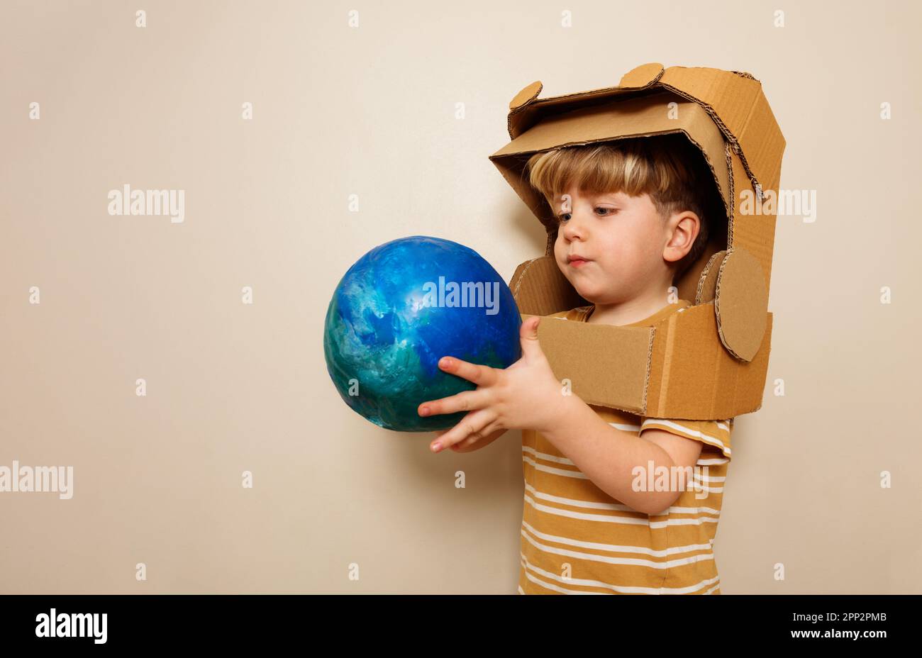 A child with cardboard astronaut helmet holds earth planet Stock Photo ...