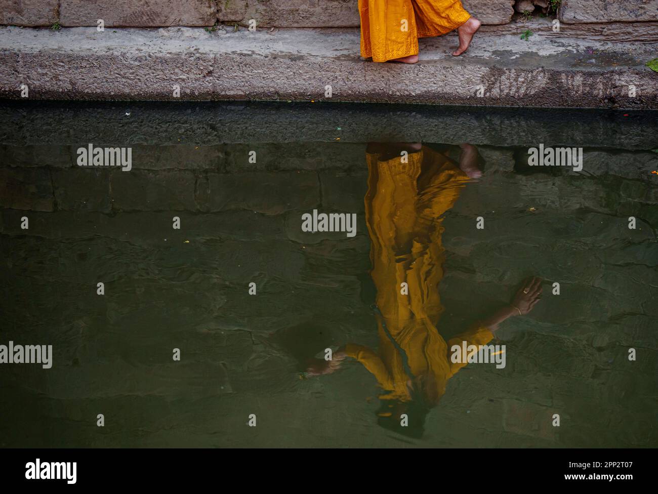 A Hindu devotee makes her way back through a narrow ledge on the banks ...